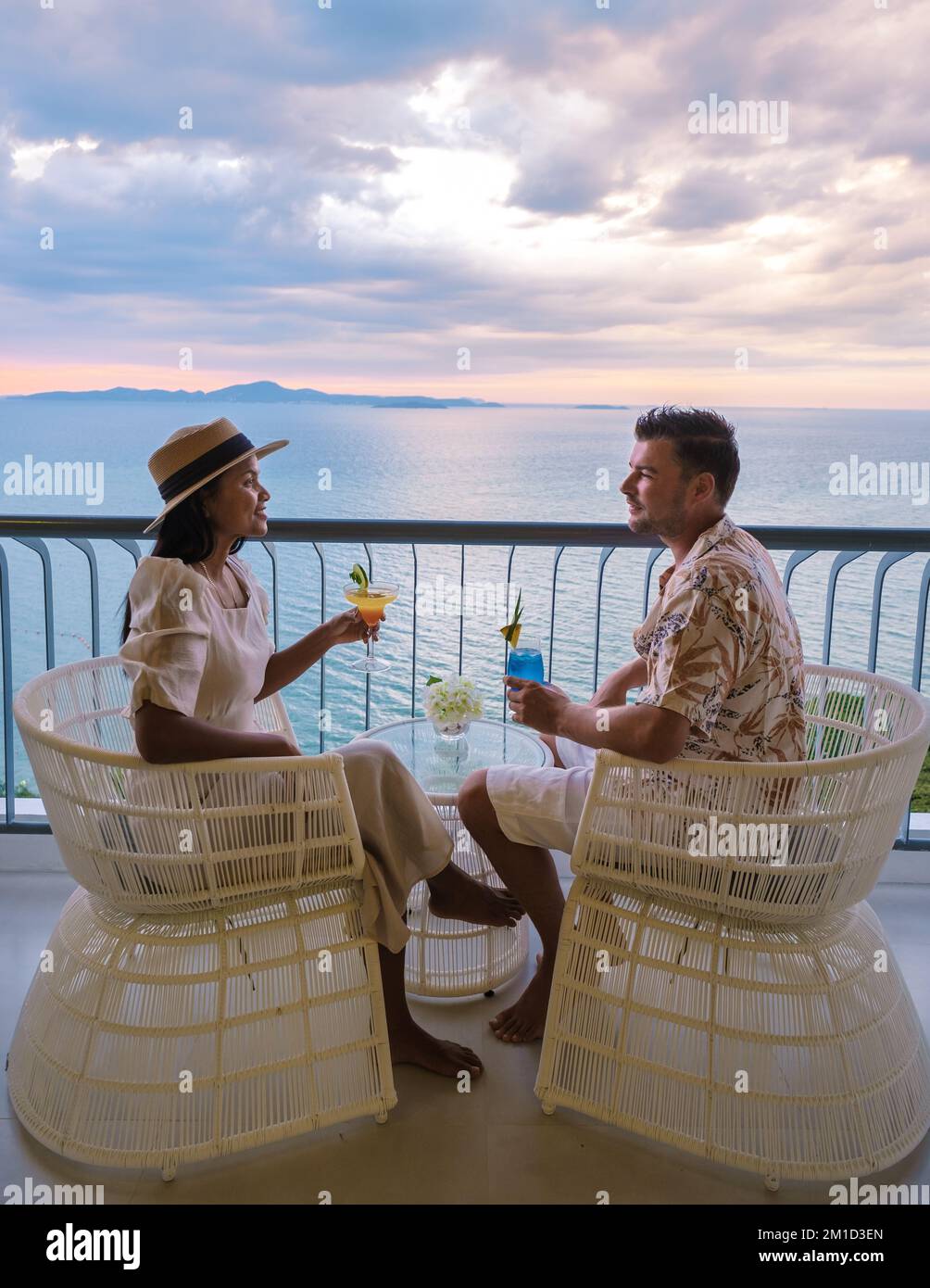 A couple of men and women looking out over blue ocean drinking ...