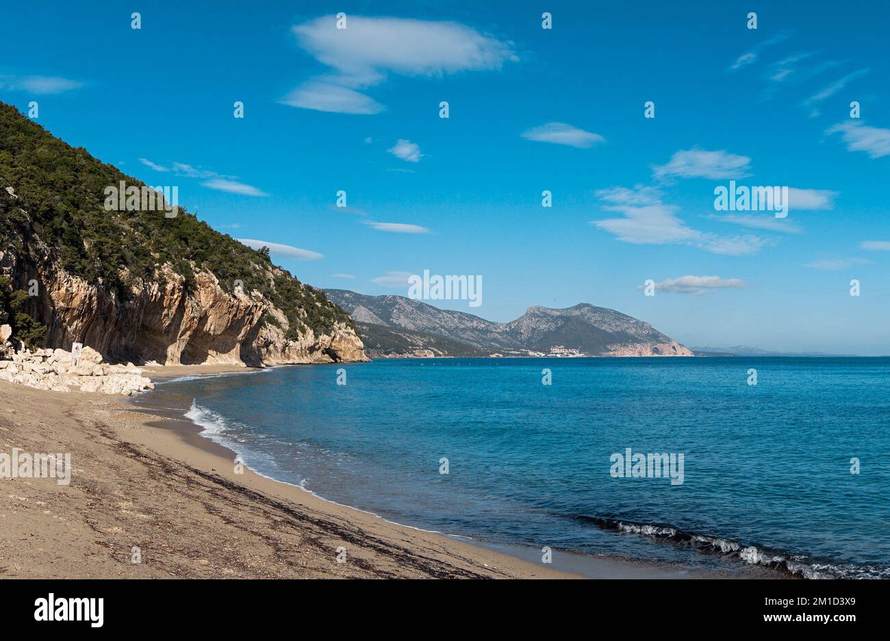 The overhanging cliffs and sandy beach at Cala Luna on the east coast ...