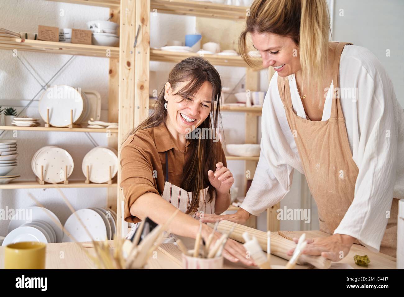 Friends with aprons in a pottery workshop preparing clay to create ...