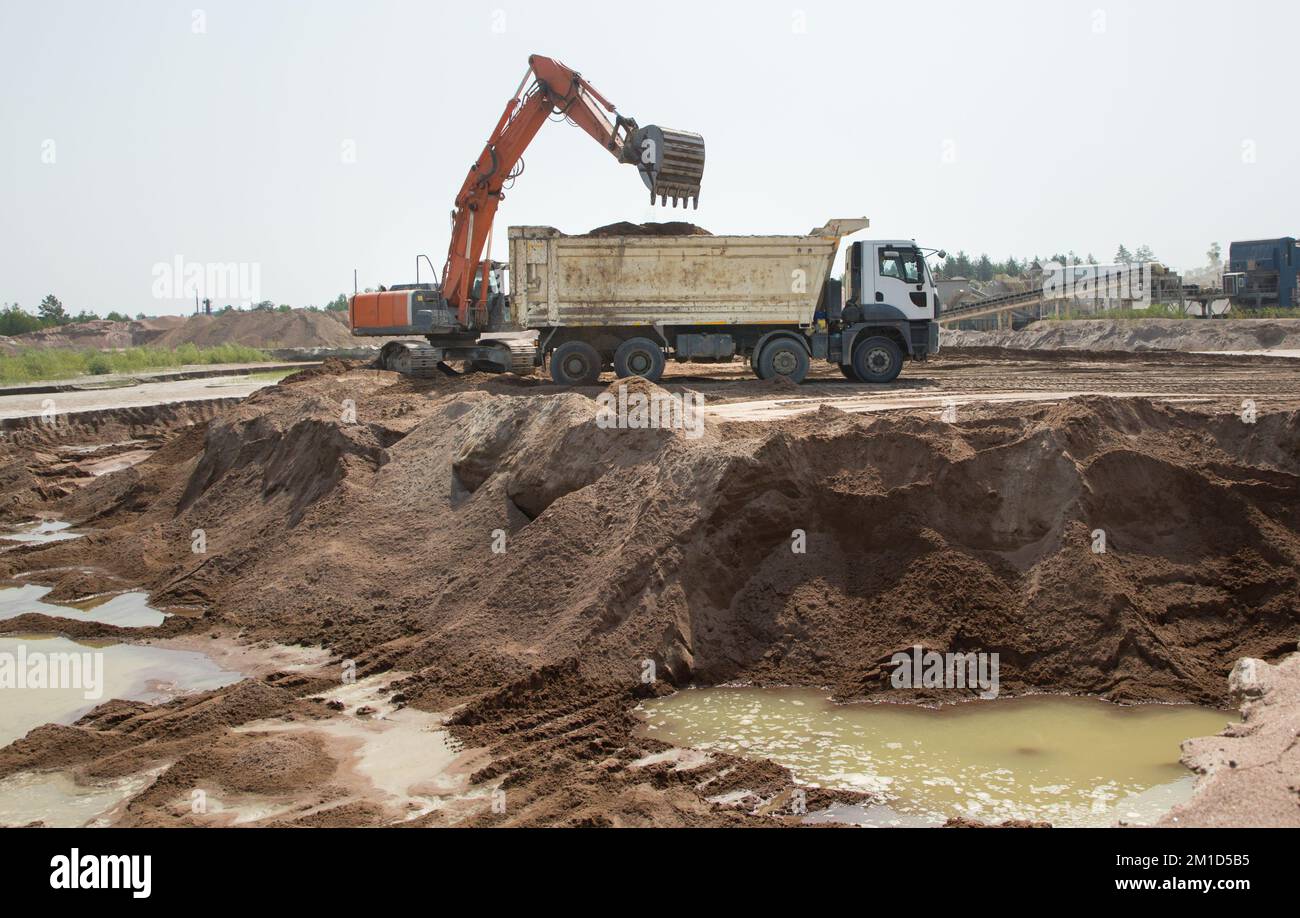 At the construction site, large working machines - an orange crawler ...