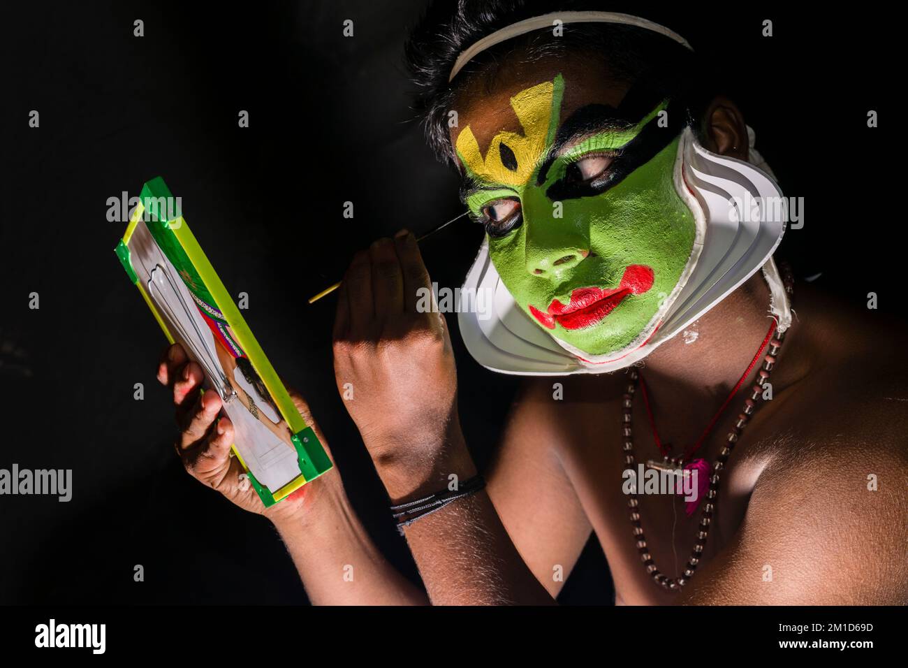 A Katakali artist is applying the make up of the character Arjun for ...