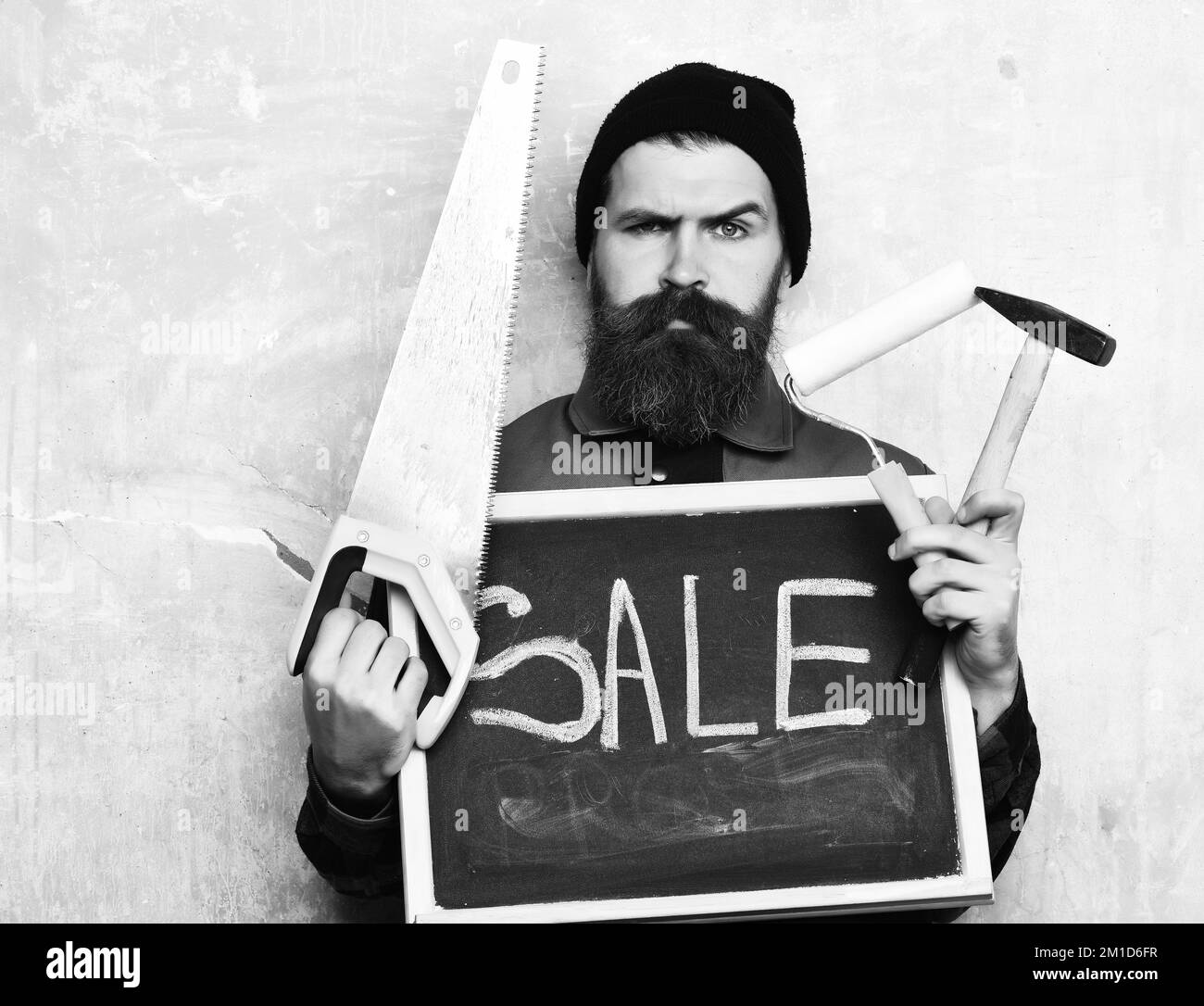 bearded foreman holding various building tools and board, serious face ...