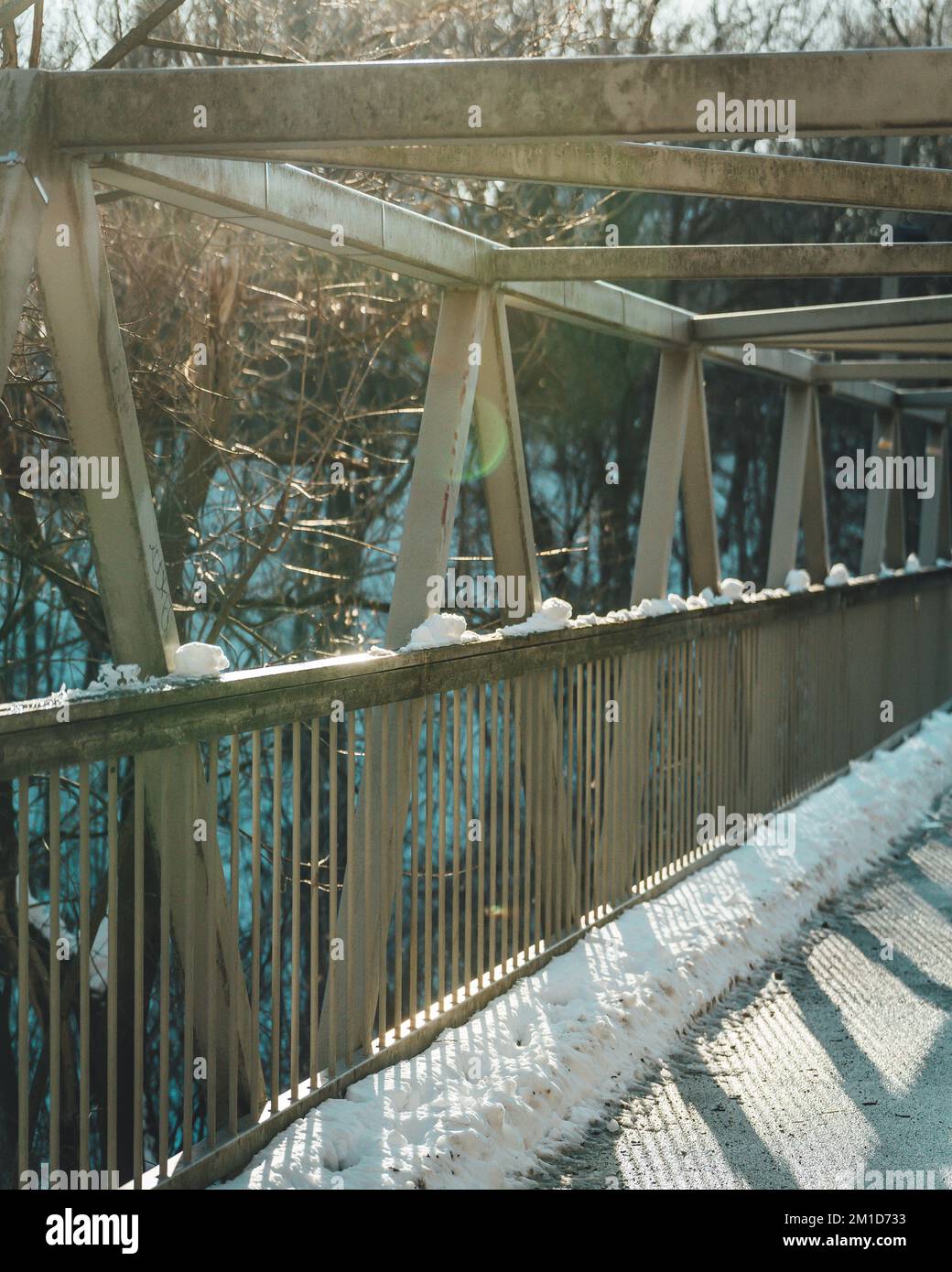 A vertical shot of a bridge railings covered in snow on a sunny winter ...