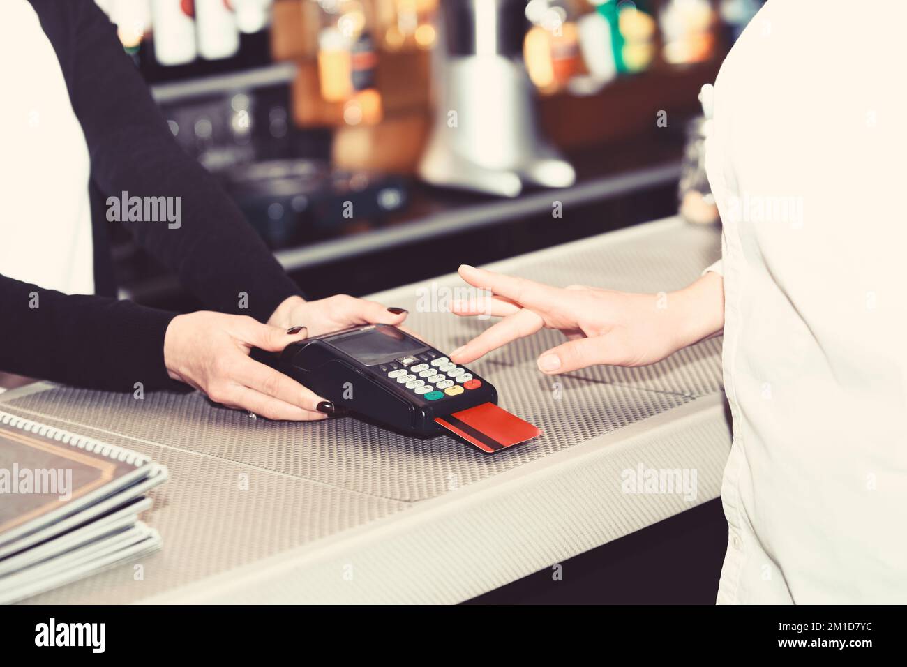 Cashiers hand holds credit card terminal on defocused background Stock ...