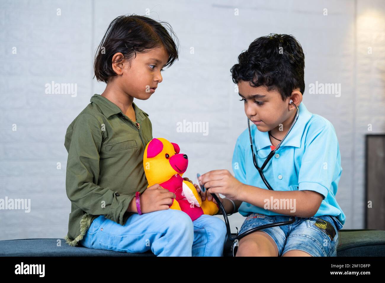 Young kids playing with stethoscope checking heartbeat of teddy bear at ...