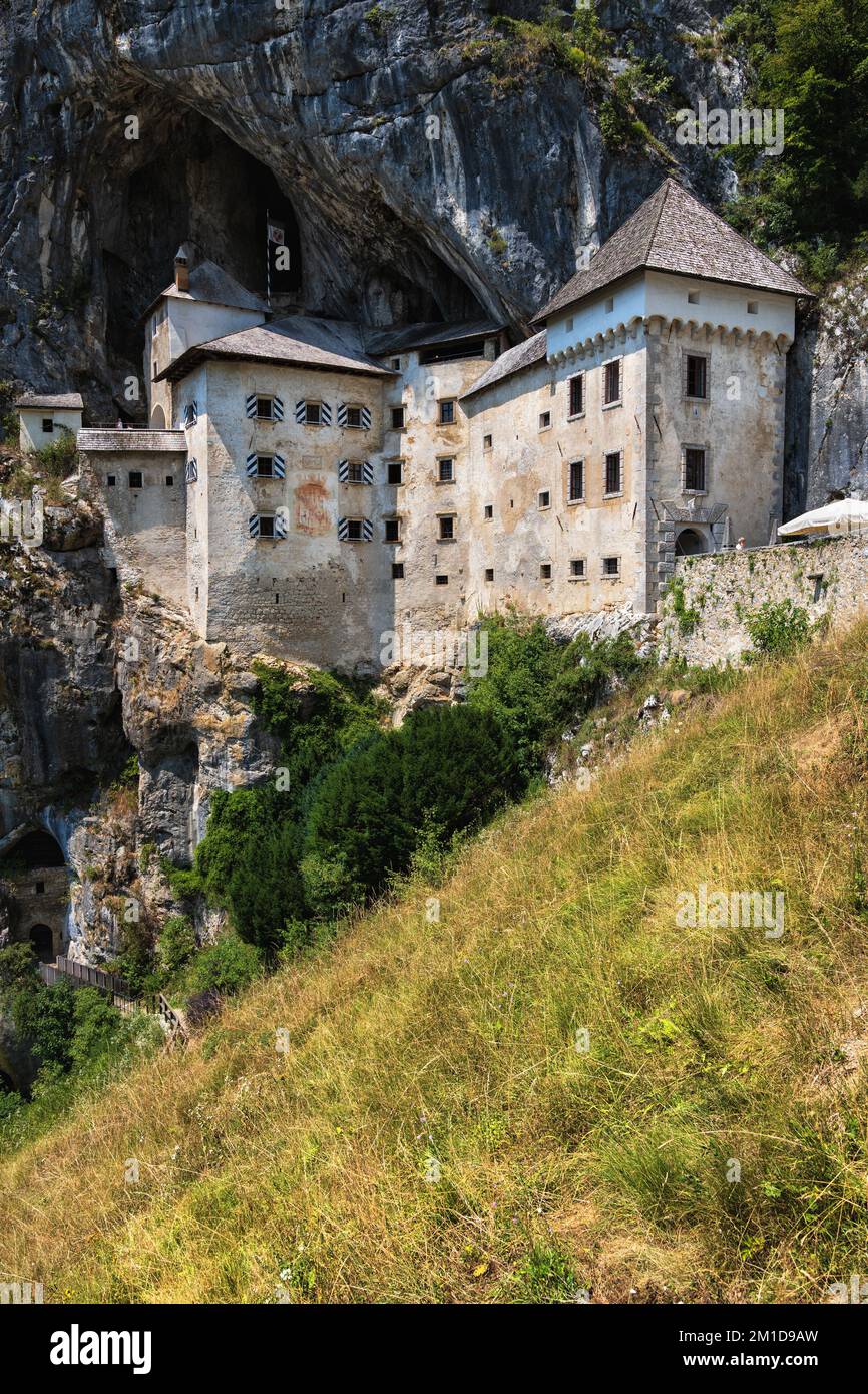 Landscape with Predjama Castle in Slovenia. Medieval cave castle in cliff with network of secret ...