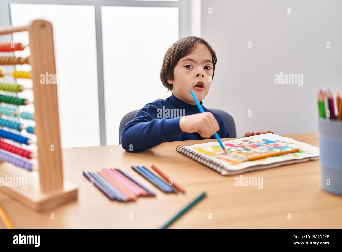 Down syndrome kid drawing on notebook at school Stock Photo - Alamy