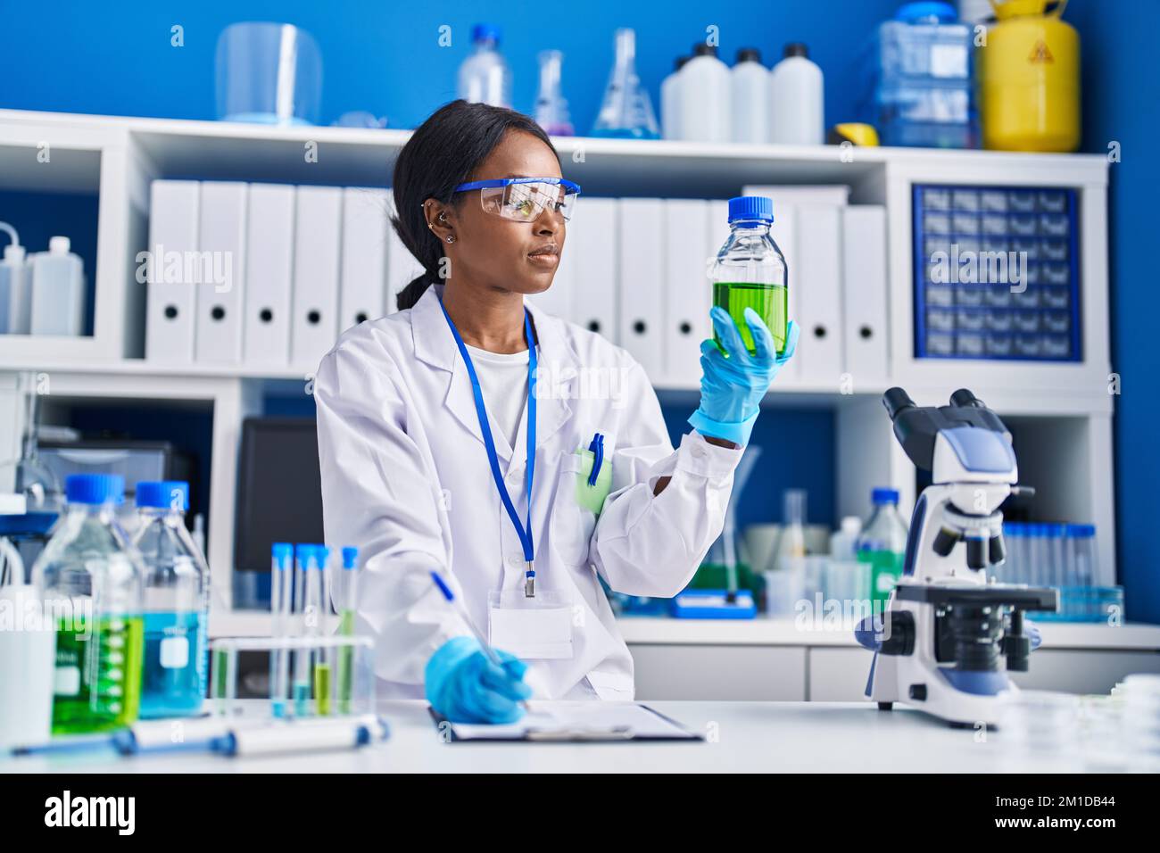 Young african american woman scientist measuring liquid at laboratory ...