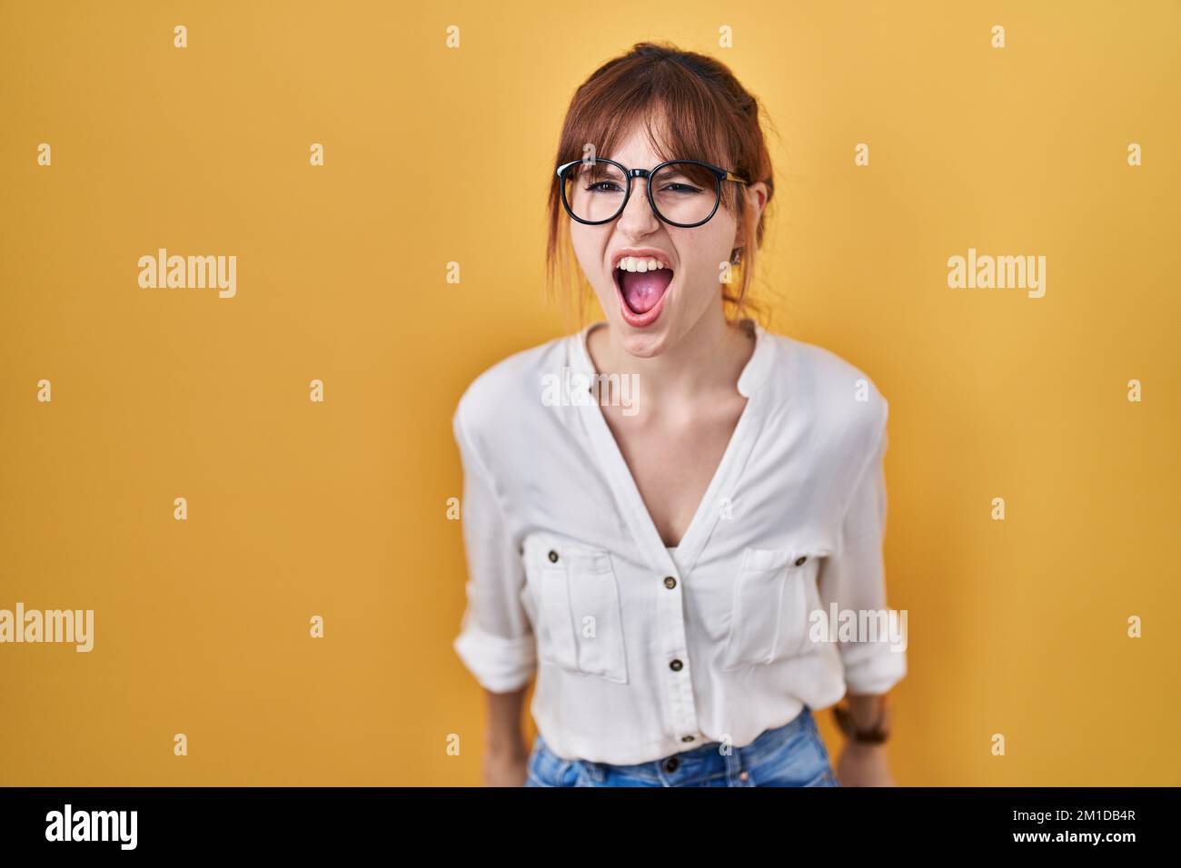 Young beautiful woman wearing casual shirt over yellow background angry ...