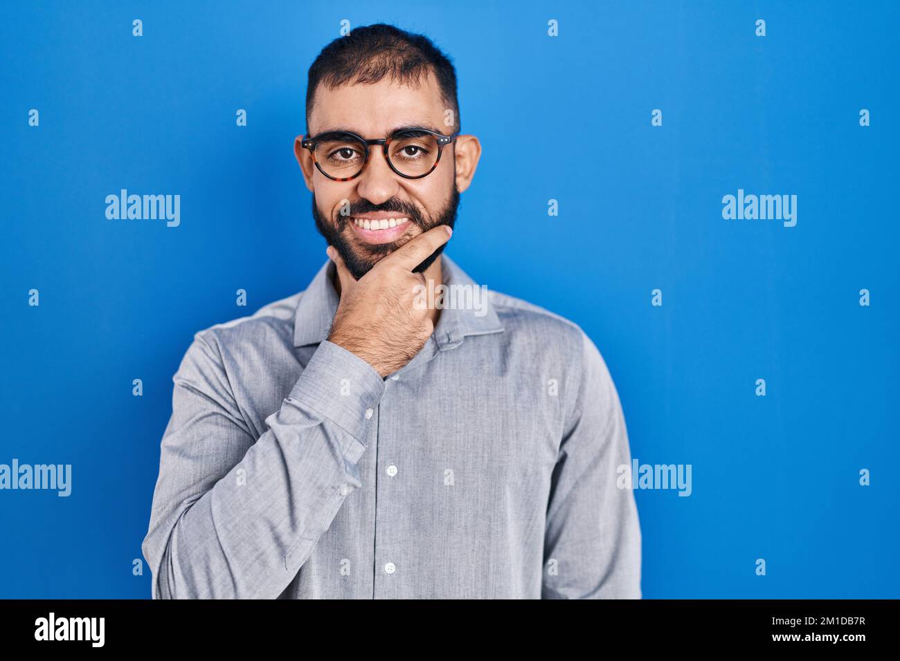 Middle east man with beard standing over blue background looking ...