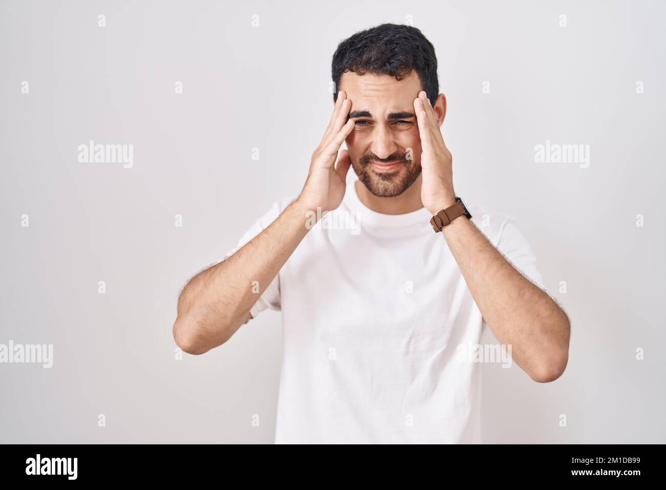 Handsome hispanic man standing over white background with hand on head ...