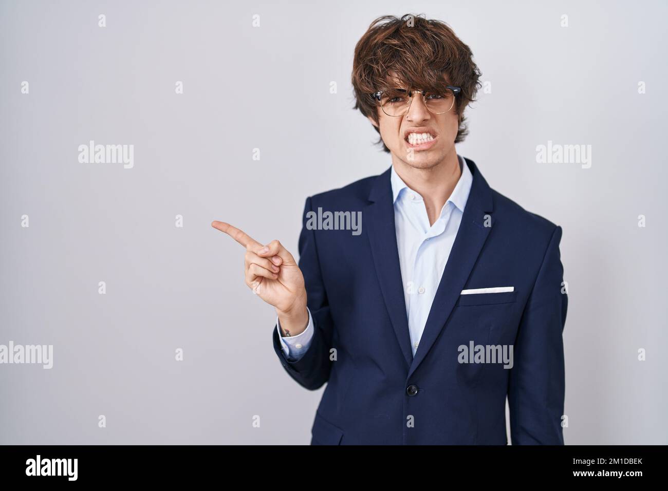 Hispanic business young man wearing glasses pointing aside worried and ...