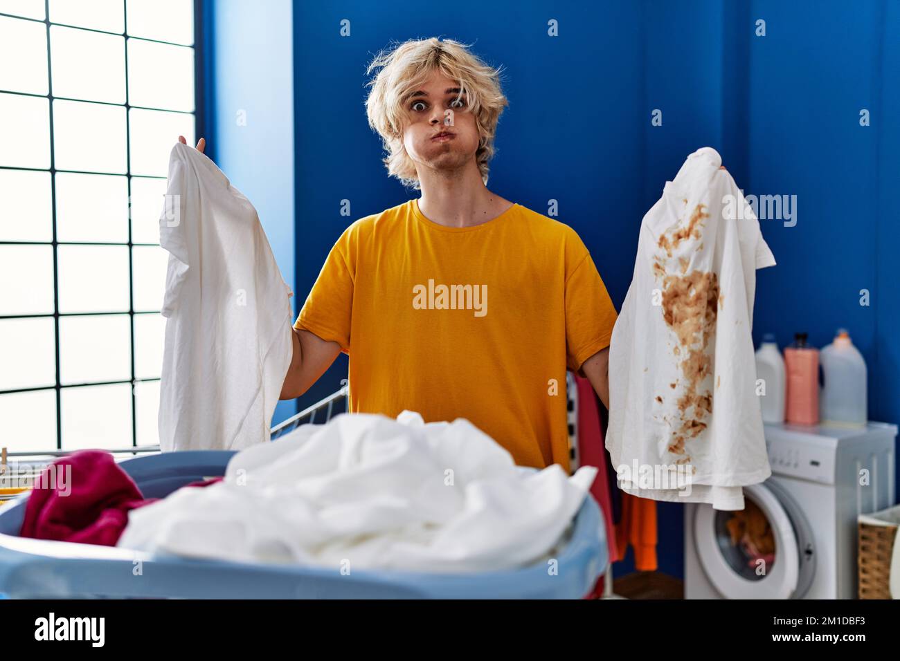 Young man holding clean white t shirt and t shirt with dirty stain ...