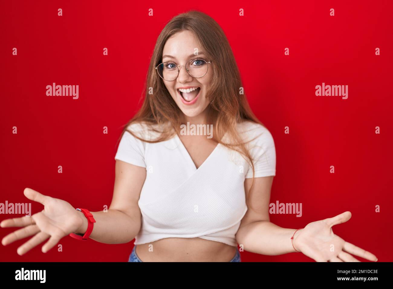 Young caucasian woman standing over red background smiling cheerful ...