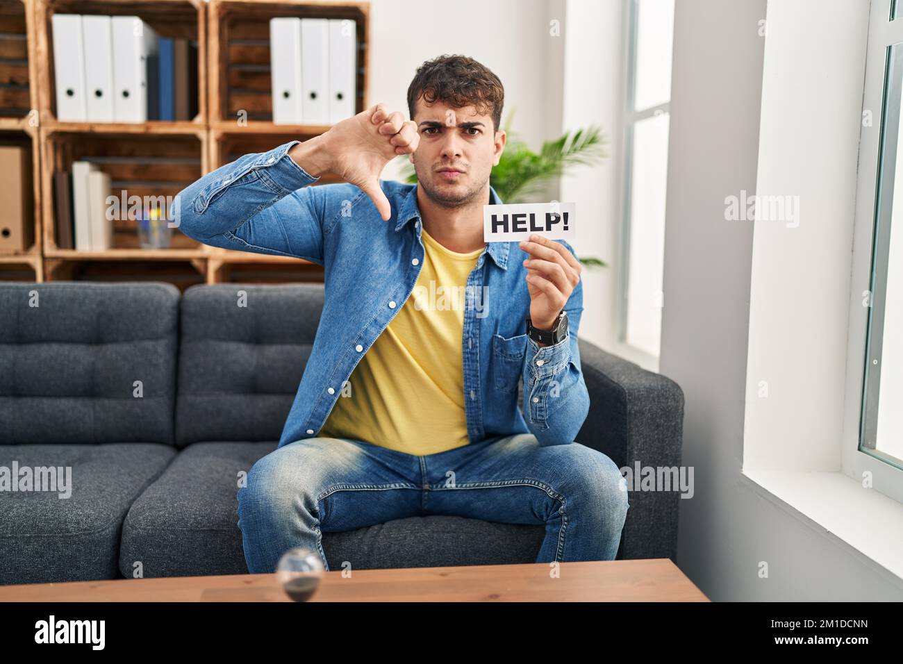 Young hispanic man at therapy asking for help with angry face, negative ...