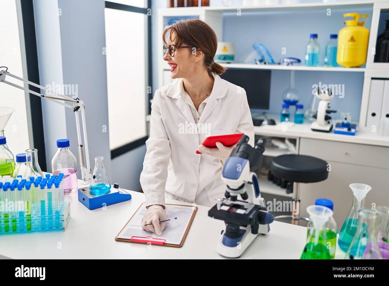 Young caucasian woman wearing scientist uniform using touchpad working at laboratory Stock Photo ...