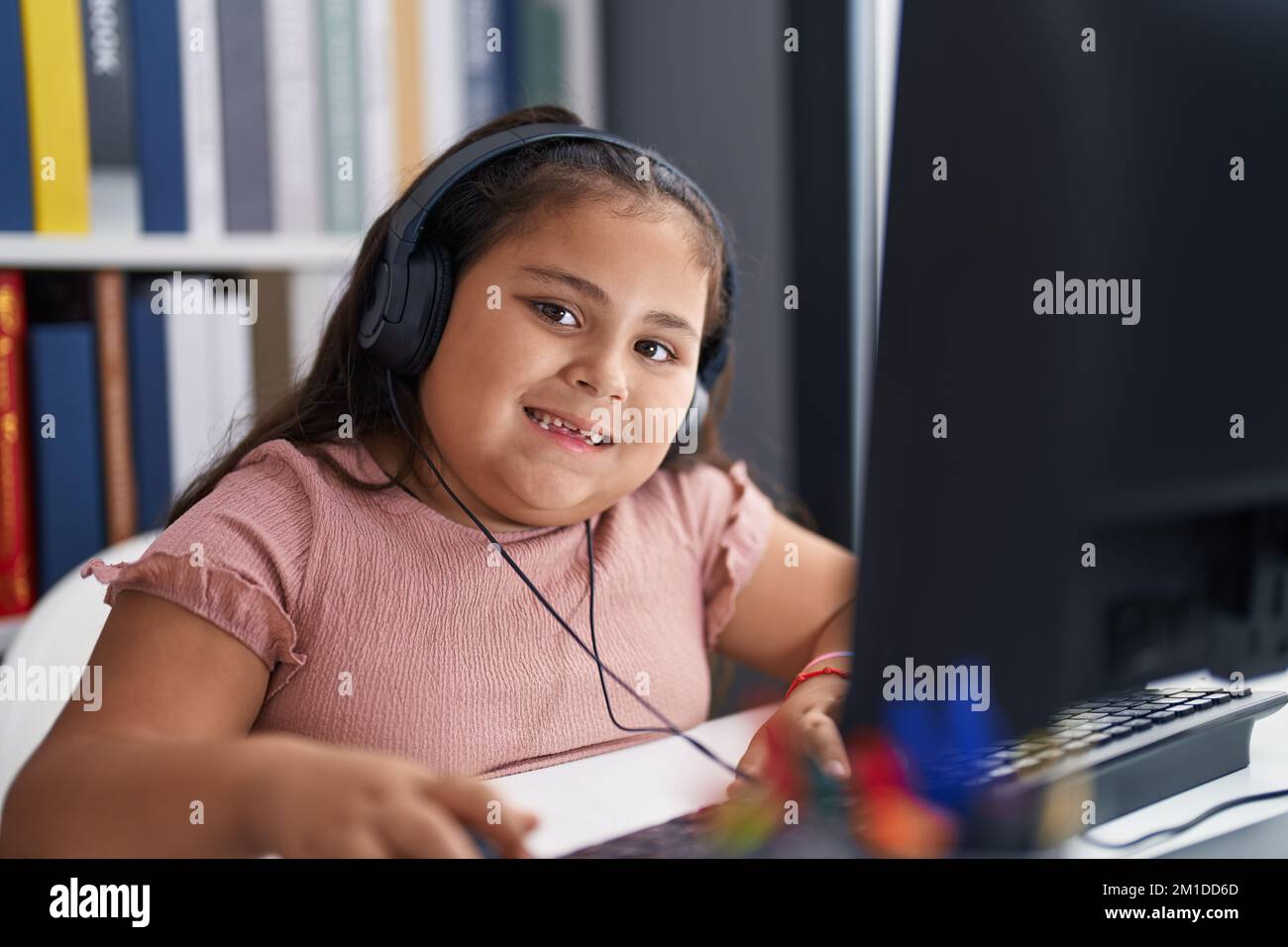 Plus size hispanic girl student using computer and headphones sitting ...