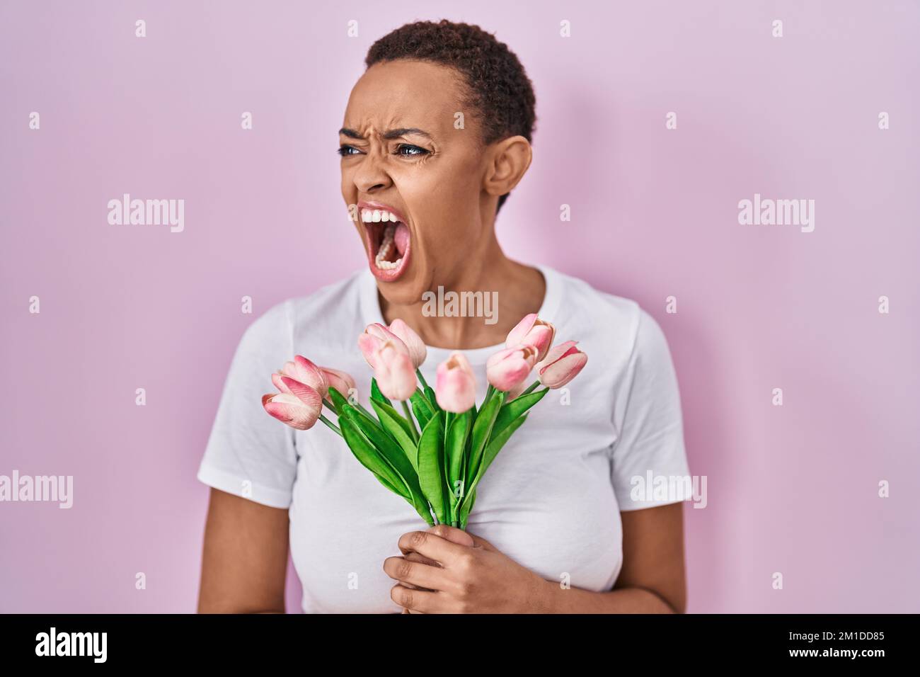 Beautiful african american woman holding bouquet of pink tulips flowers ...