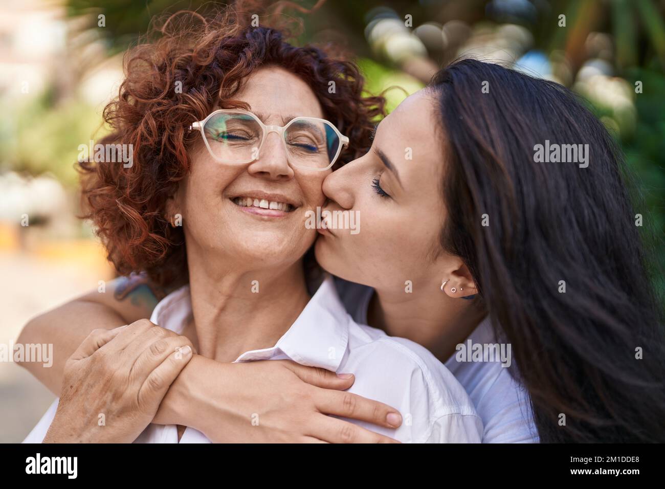 Two women mother and daughter hugging each other and kissing at park Stock Photo - Alamy