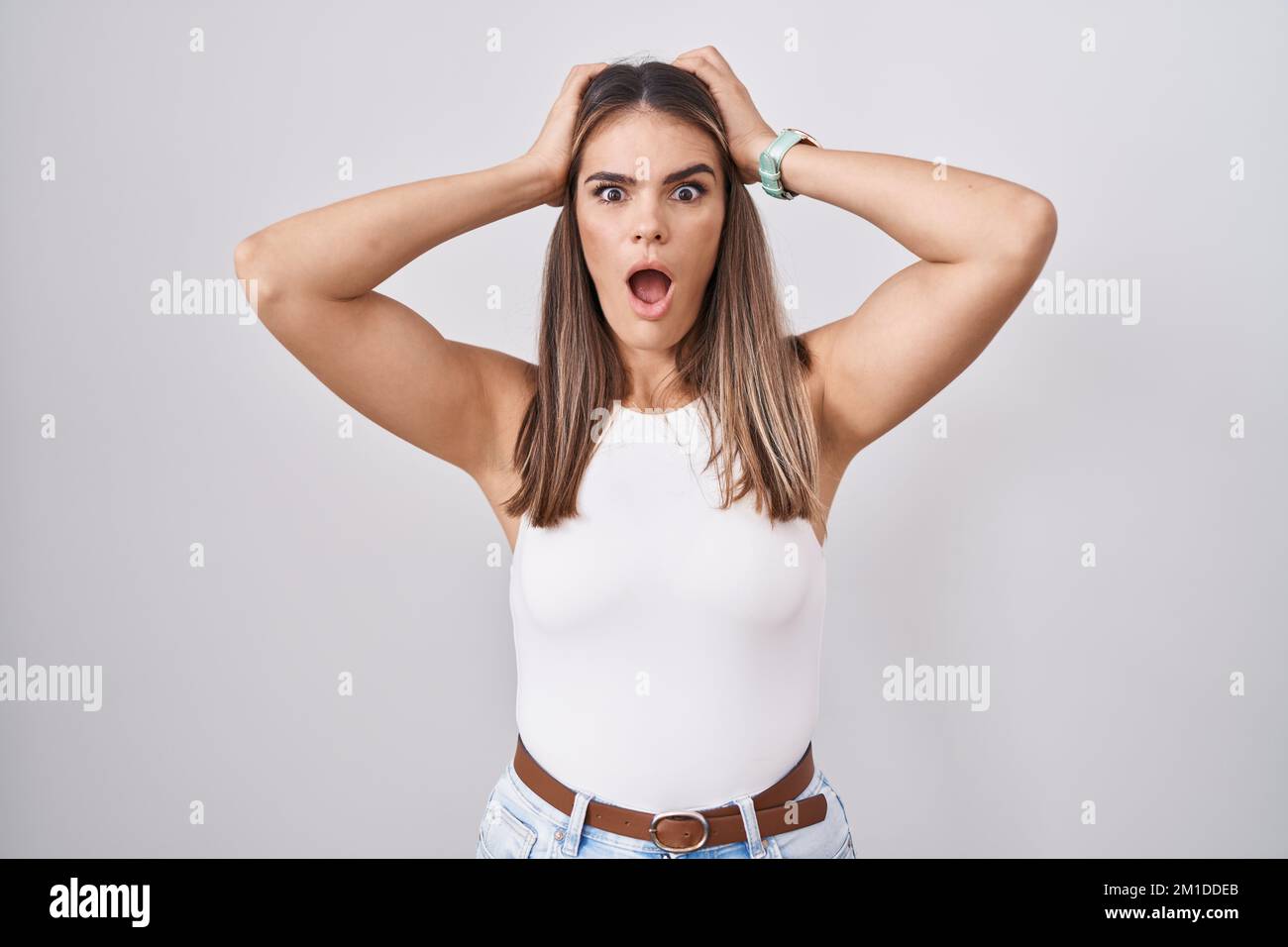 Hispanic young woman standing over white background crazy and scared ...