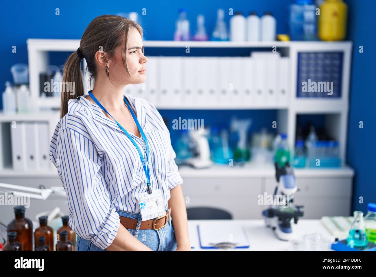 Young beautiful woman working at scientist laboratory looking to side ...
