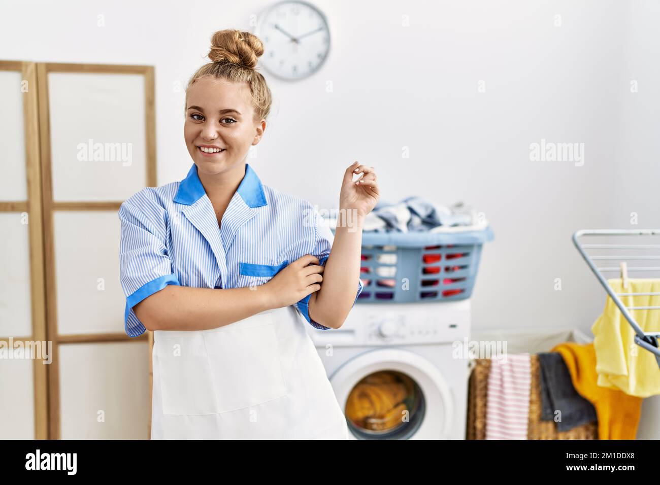 Young caucasian woman wearing cleaner uniform at the laundry room with ...