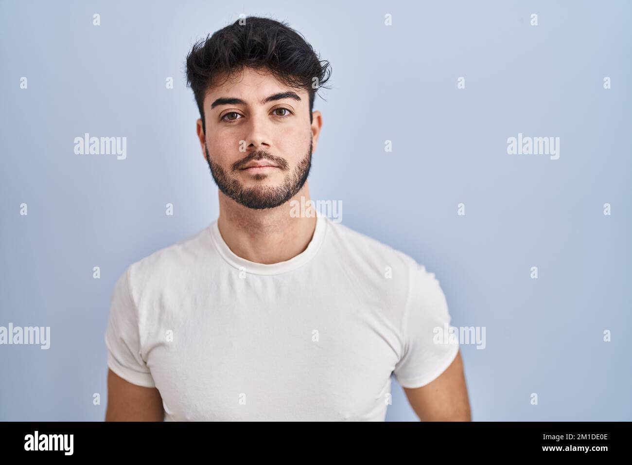 Hispanic man with beard standing over white background relaxed with ...