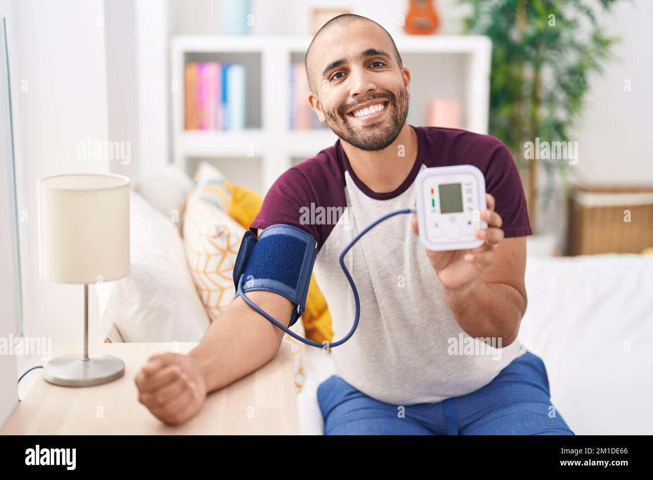 Young latin man measuring pulse using tensiometer at bedroom Stock ...