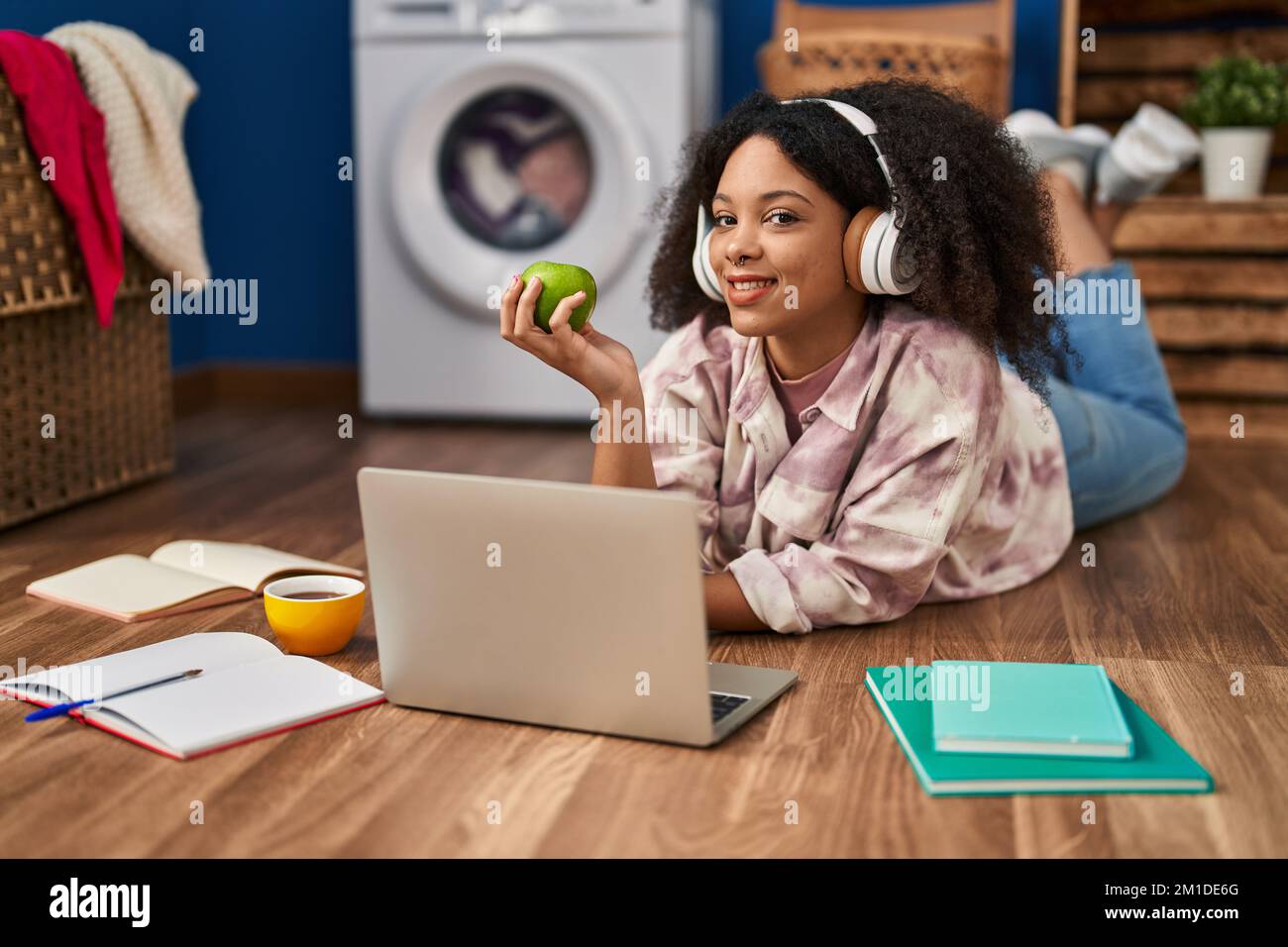 Young african american woman waiting for washing machine studying and ...