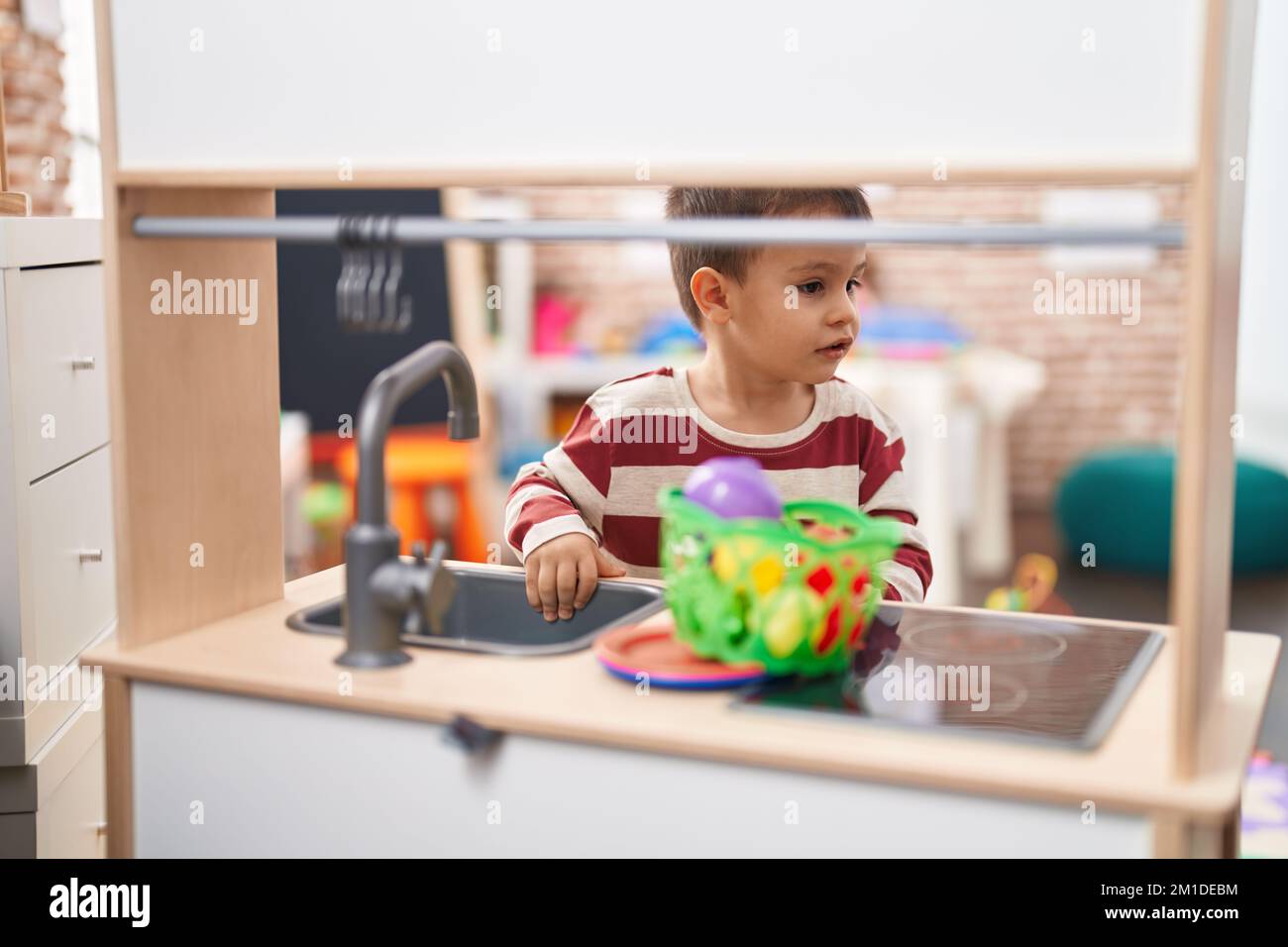 Adorable toddler playing with play kitchen standing at kindergarten ...
