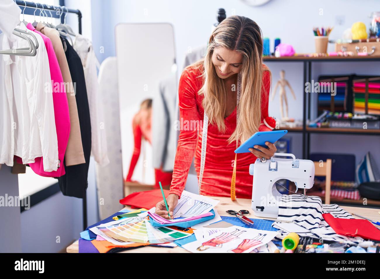 Young blonde woman tailor using touchpad drawing clothing design at ...
