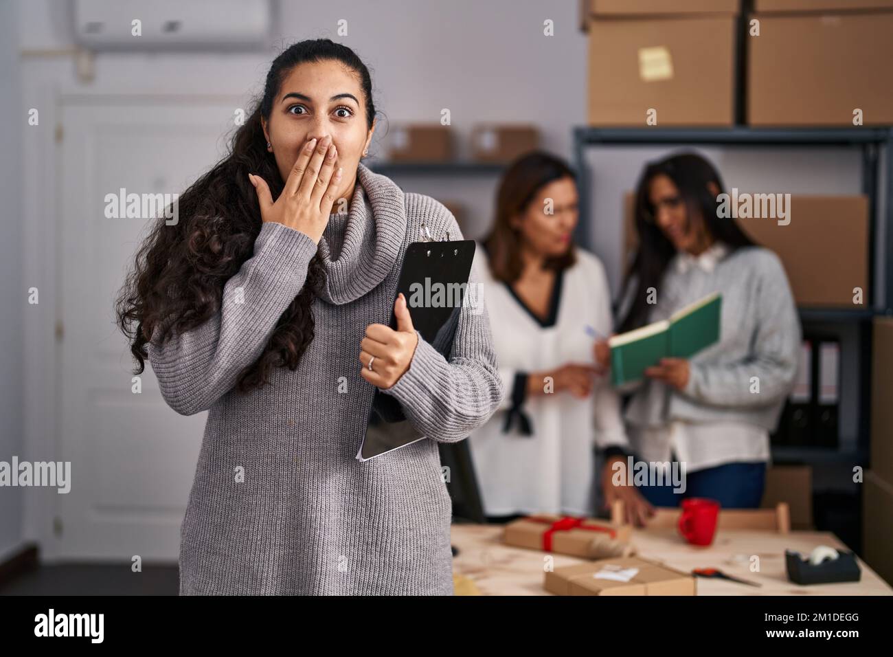 Three women working at small business ecommerce covering mouth with ...