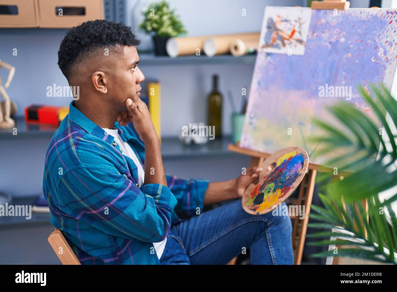 Young latin man artist drawing with doubt expression at art studio ...