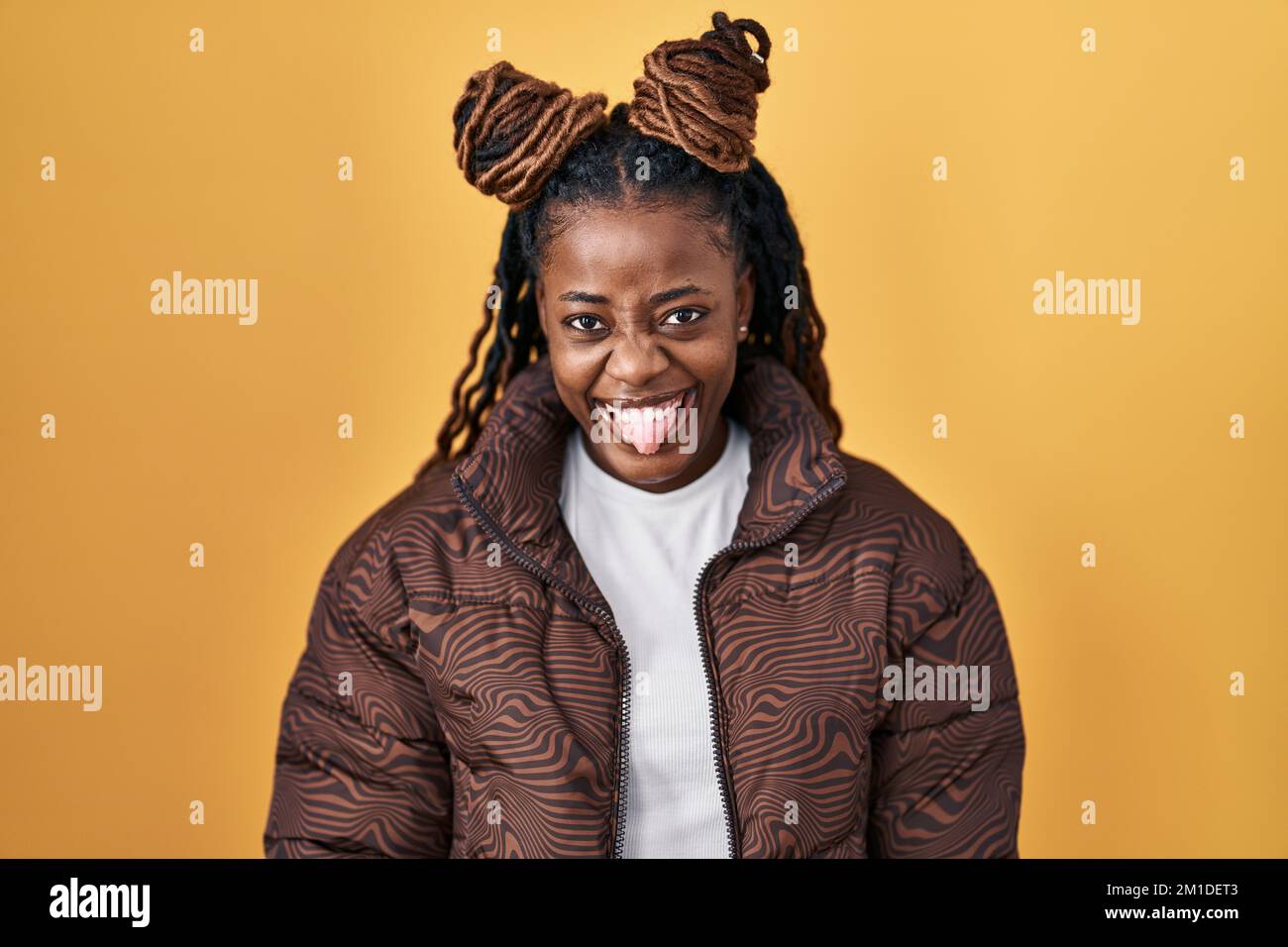 African woman with braided hair standing over yellow background ...