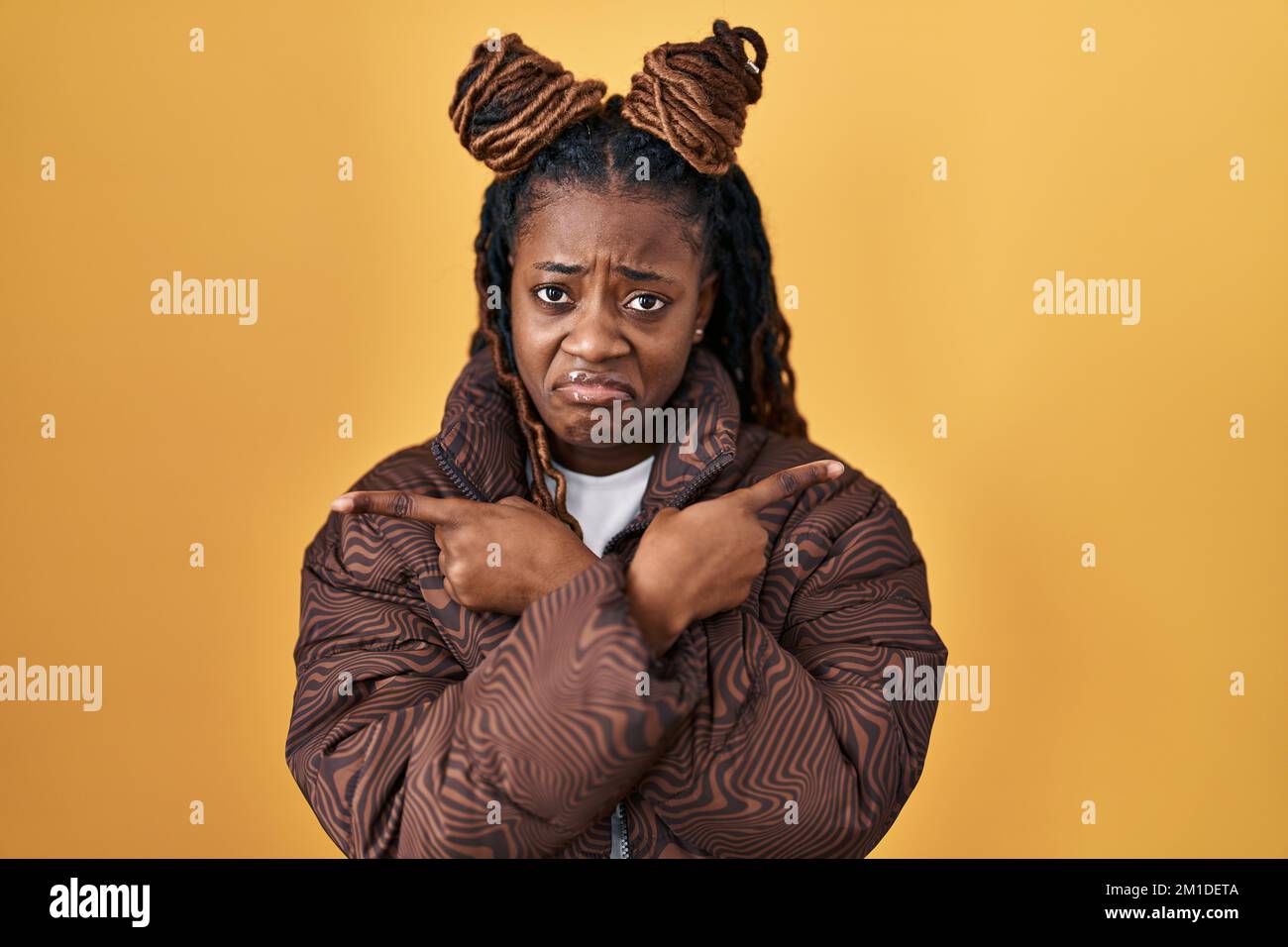 African woman with braided hair standing over yellow background ...