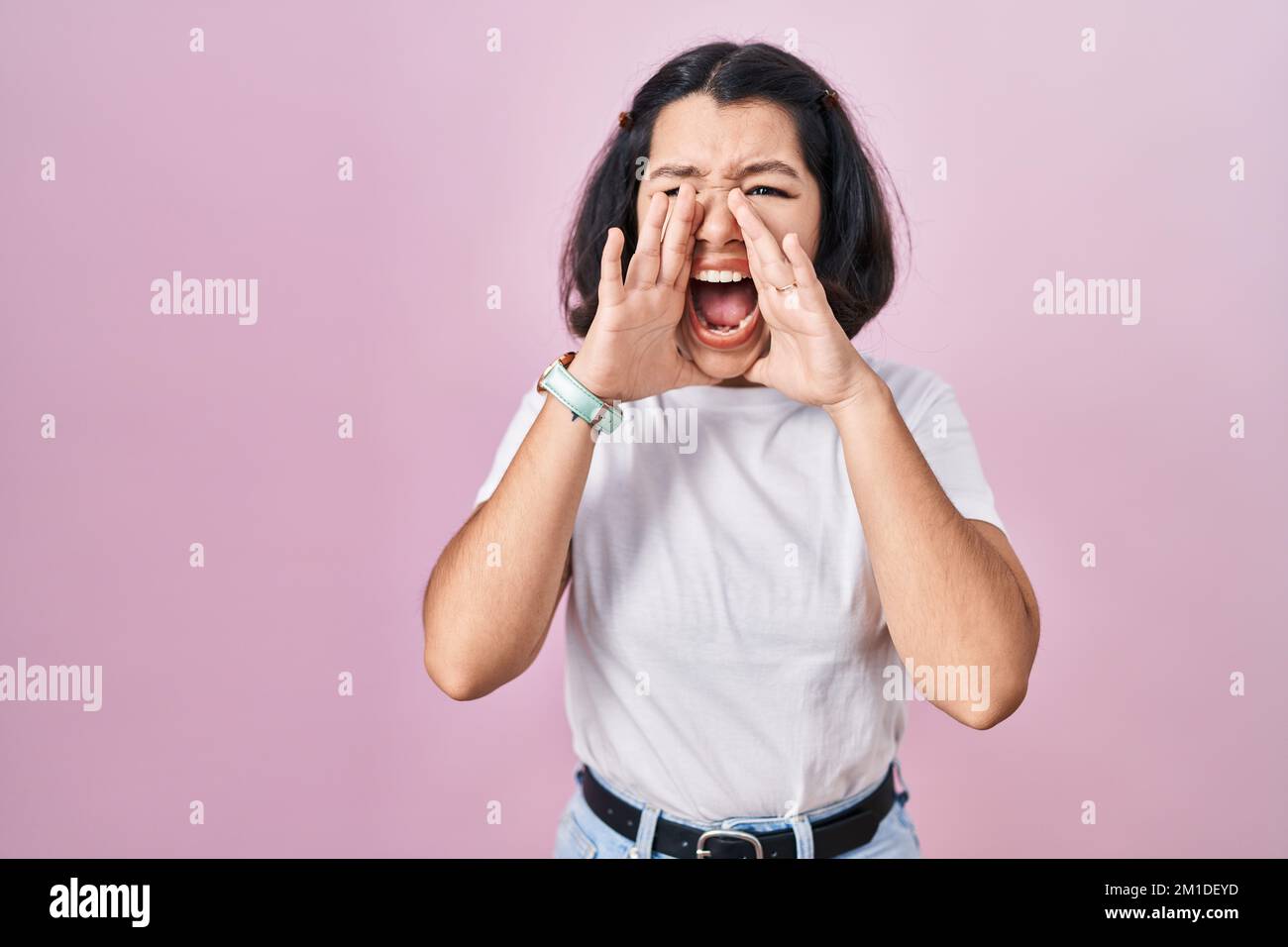 Young hispanic woman wearing casual white t shirt over pink background ...