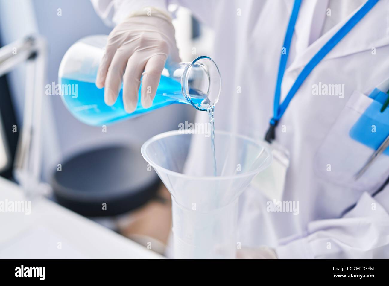 Young woman scientist pouring liquid on test tube at laboratory Stock ...