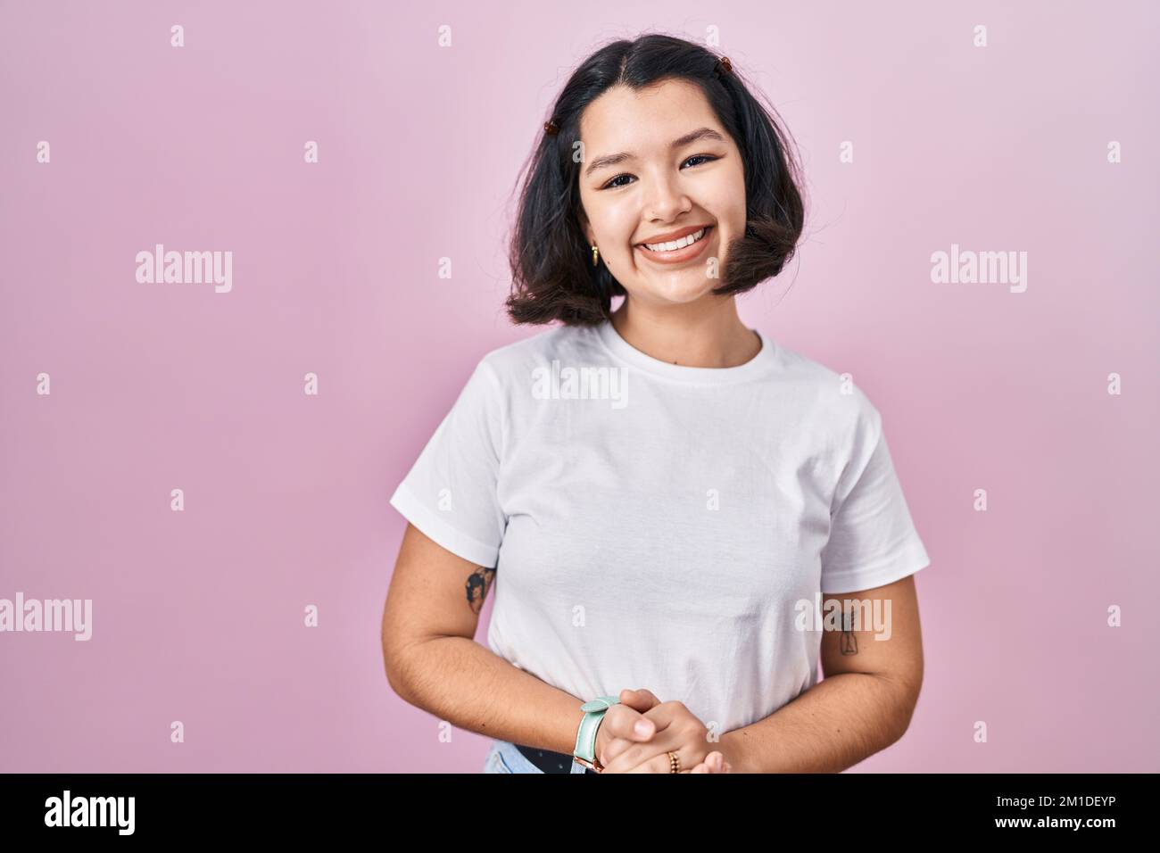 Young hispanic woman wearing casual white t shirt over pink background ...