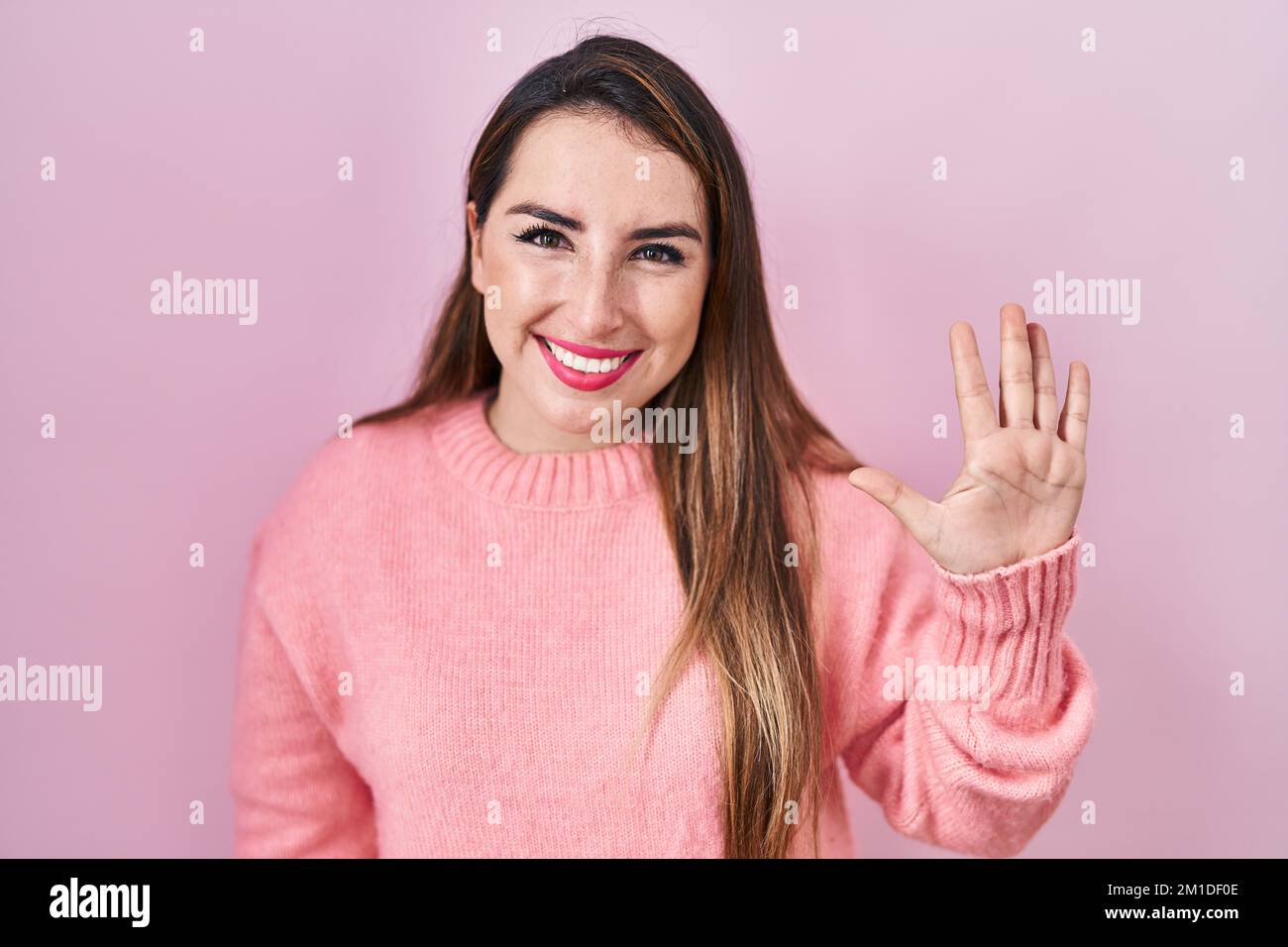 Young hispanic woman standing over pink background showing and pointing ...
