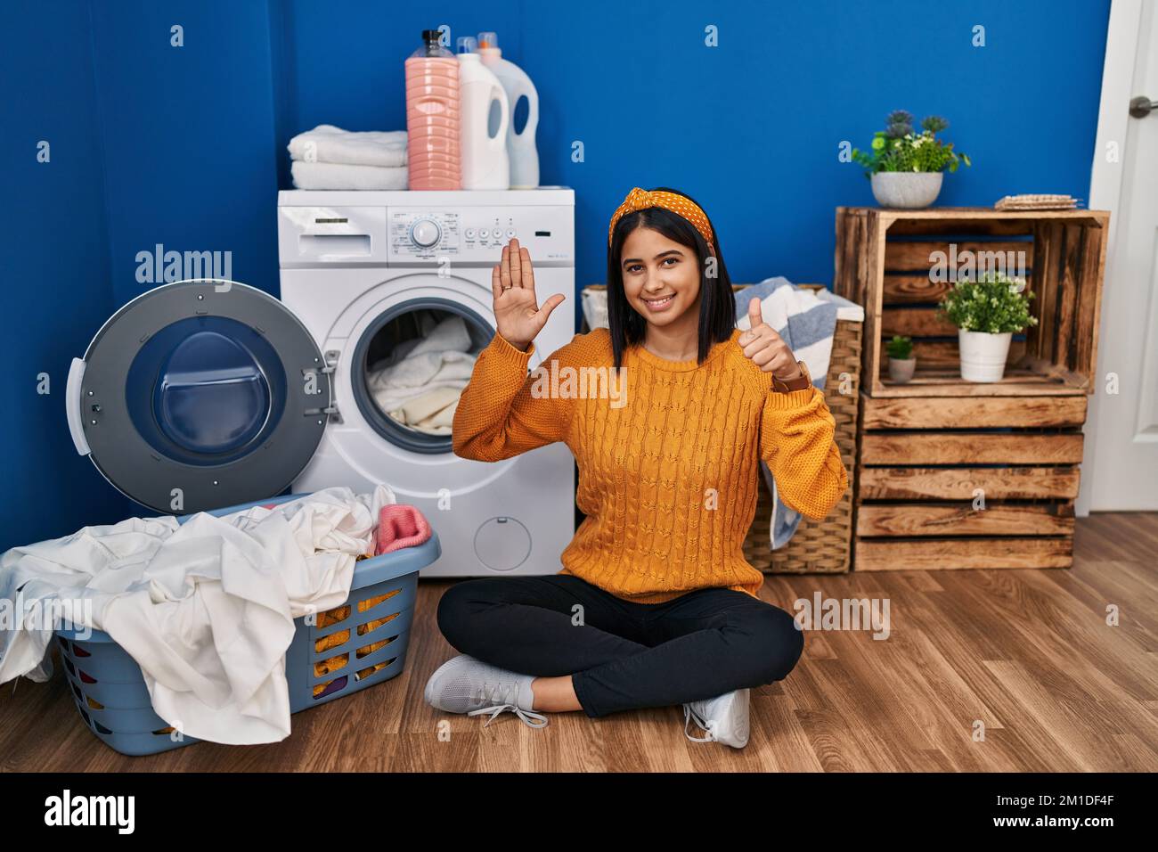 Young hispanic woman doing laundry showing and pointing up with fingers ...