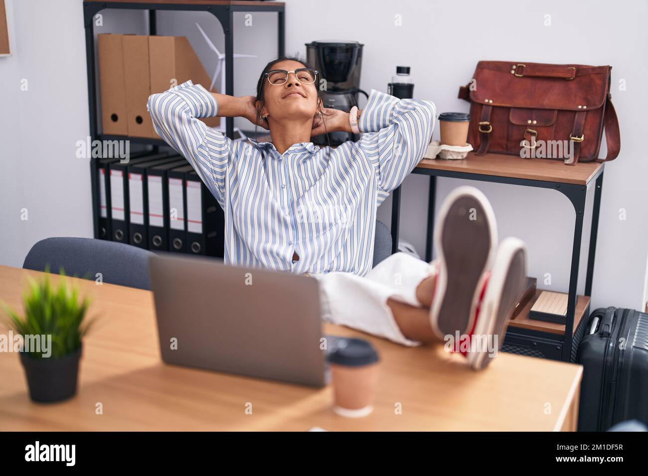 Young beautiful hispanic woman business worker using laptop relaxed ...