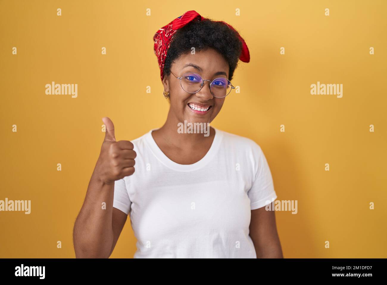 Young african american woman standing over yellow background doing ...