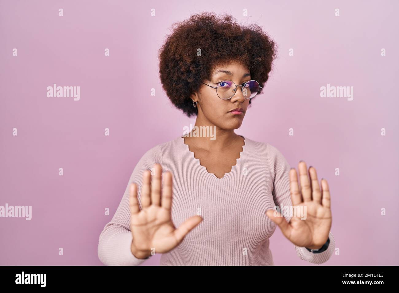 Young african american woman standing over pink background moving away ...