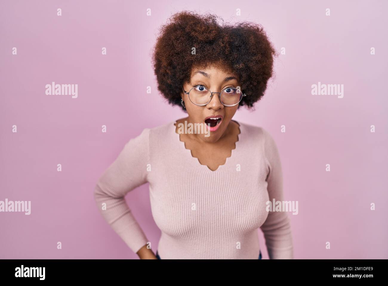 Young african american woman standing over pink background afraid and ...