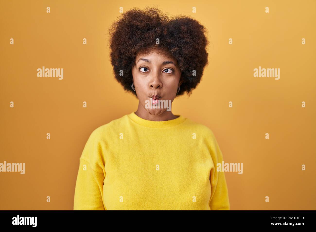 Young african american woman standing over yellow background making ...