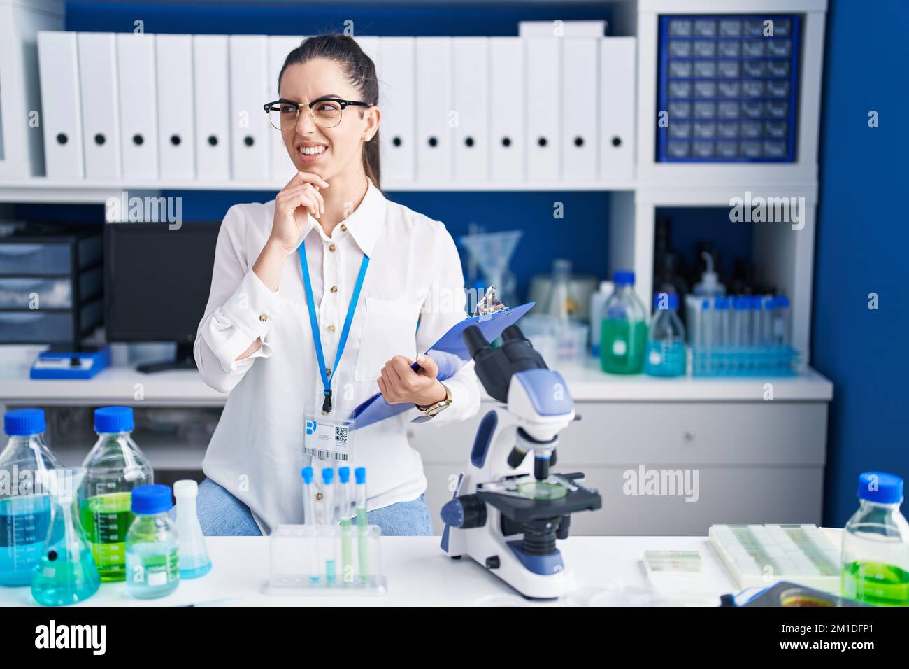 Young brunette woman working at scientist laboratory thinking worried ...