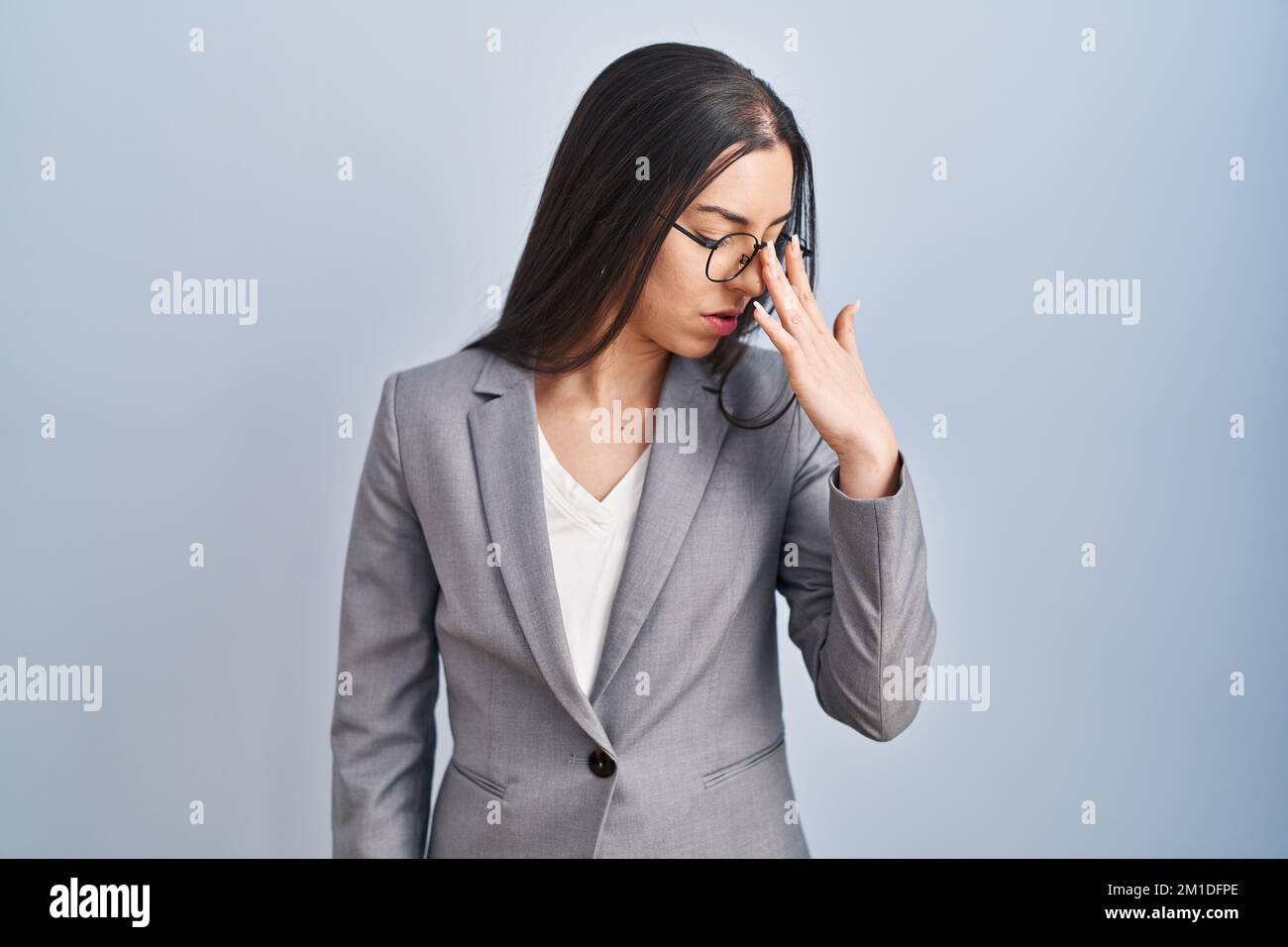 Hispanic business woman wearing glasses tired rubbing nose and eyes ...
