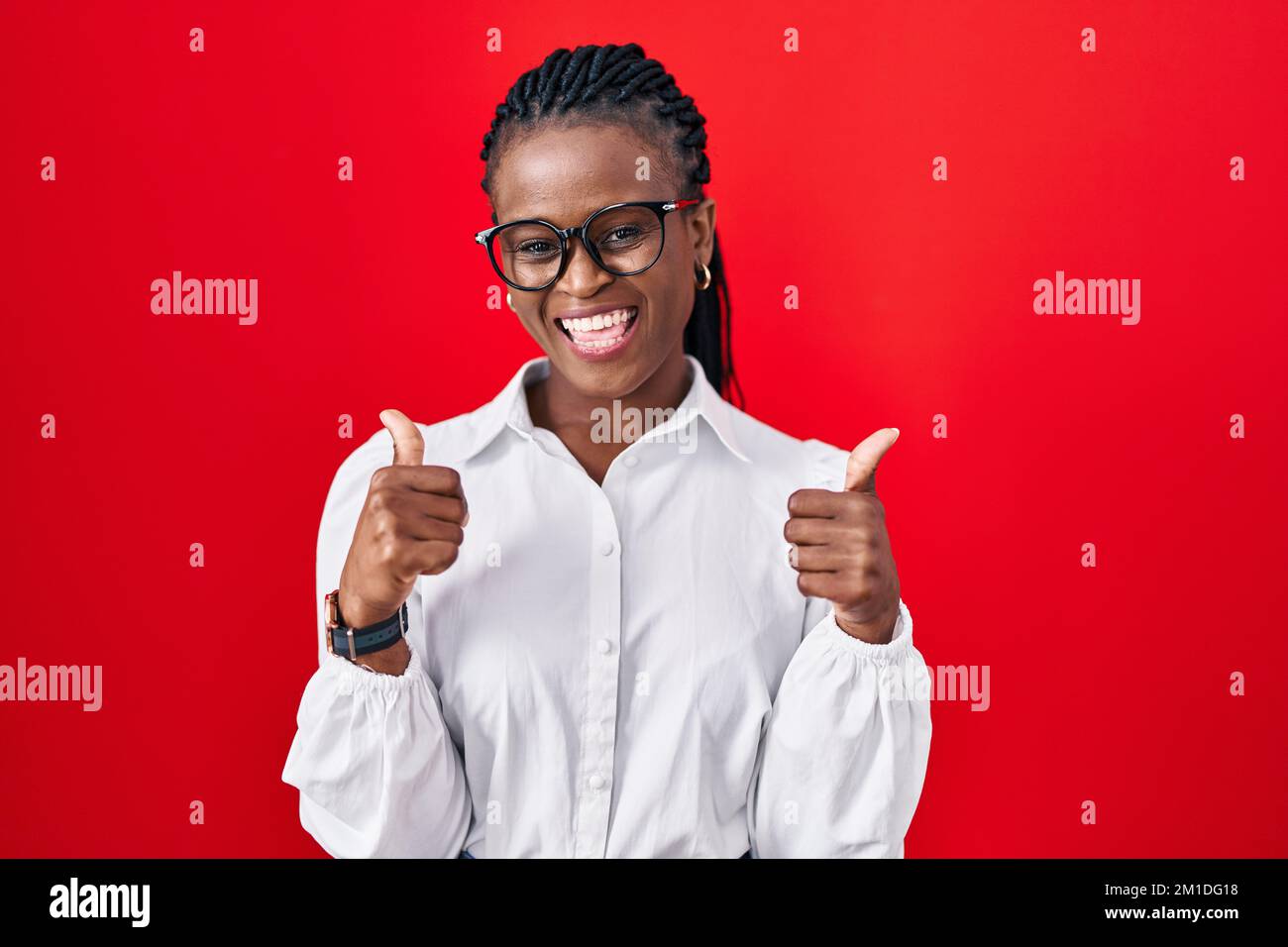 African woman with braids standing over red background success sign ...