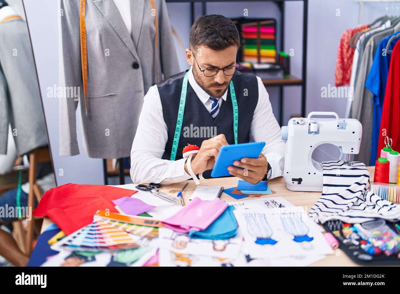 Young hispanic man tailor drawing on touchpad at tailor shop Stock ...
