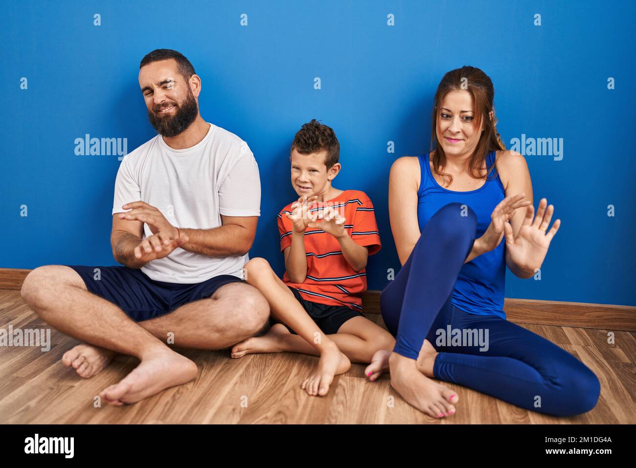 Family of three sitting on the floor at home disgusted expression ...
